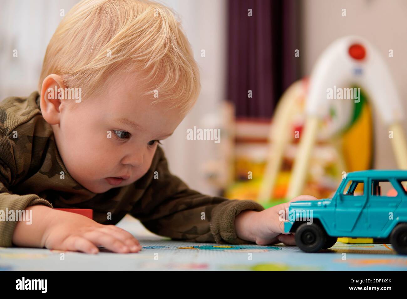 Little boy with blond hair playing with blue car. high quality Stock ...