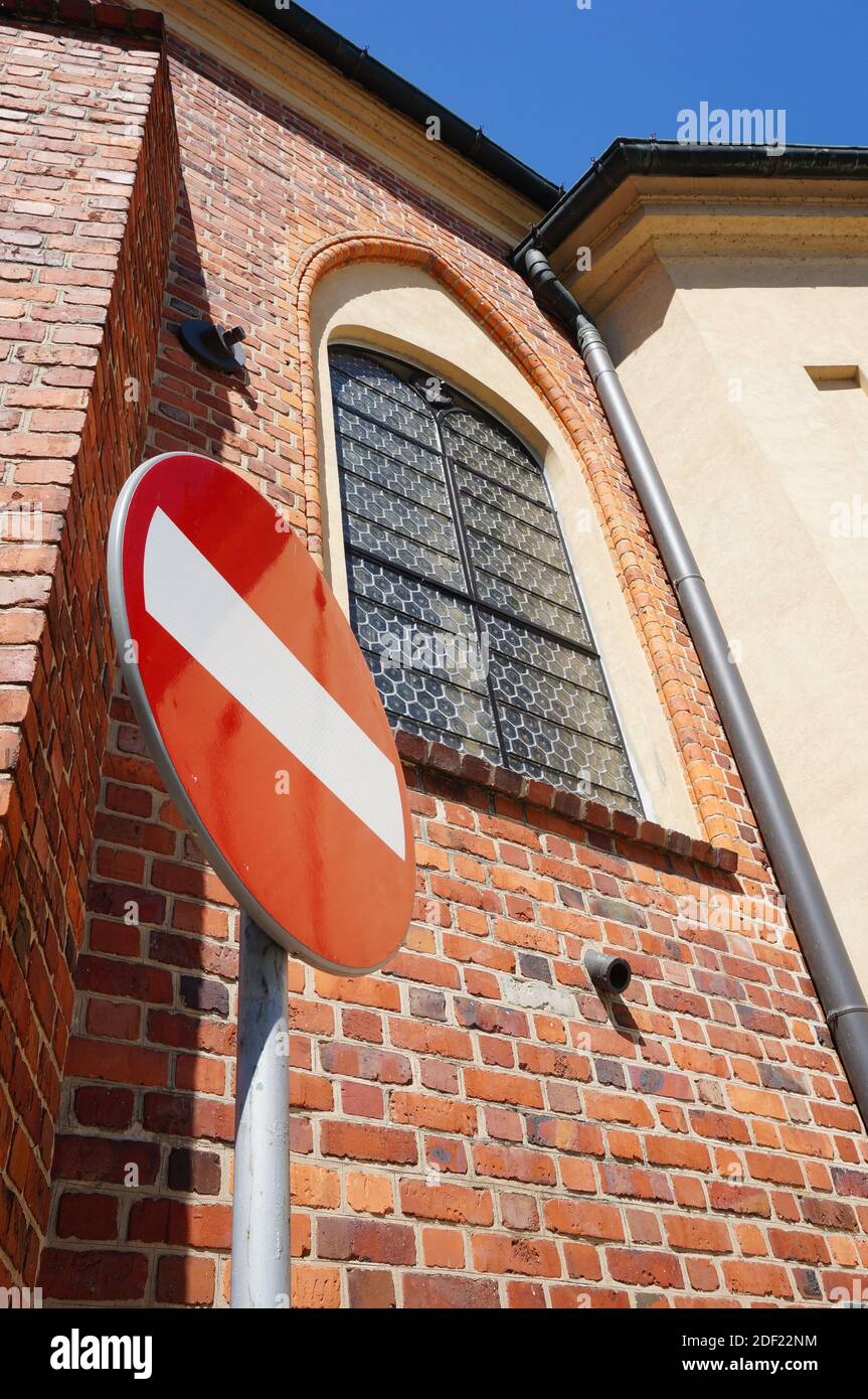 A vertical low angle shot of a red warning stop sign near a brick wall ...