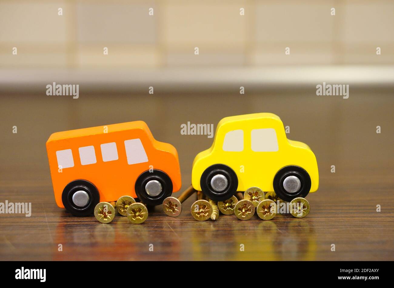 A closeup shot of two wooden colorful toy cars on golden screws on top ...