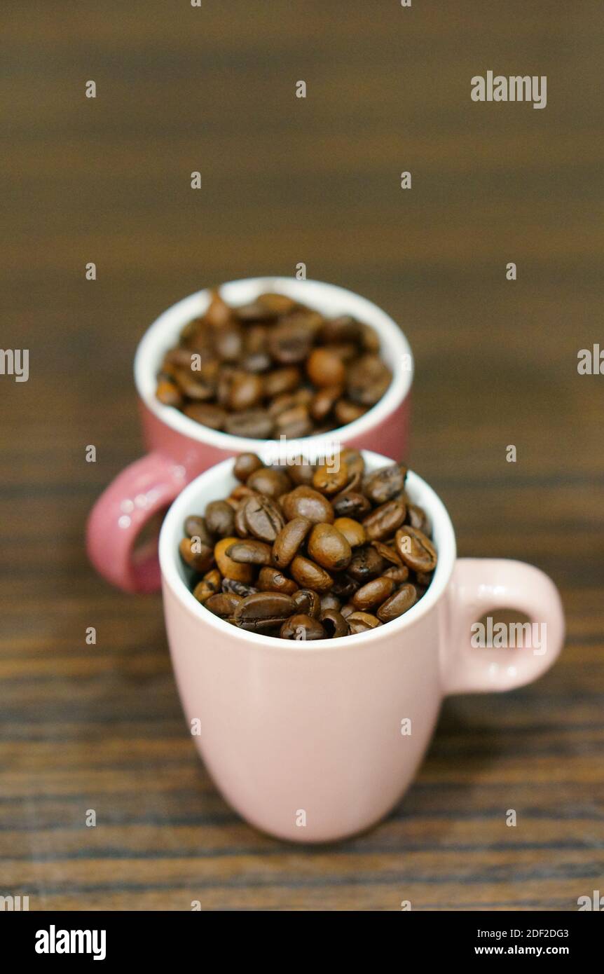 A vertical shot of coffee beans in cups on a wooden table Stock Photo ...