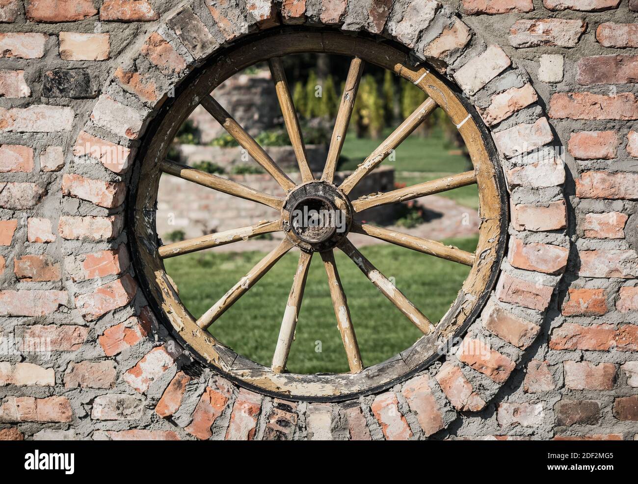 A closeup shot of a circular opening in a wall and a wooden wheel ...