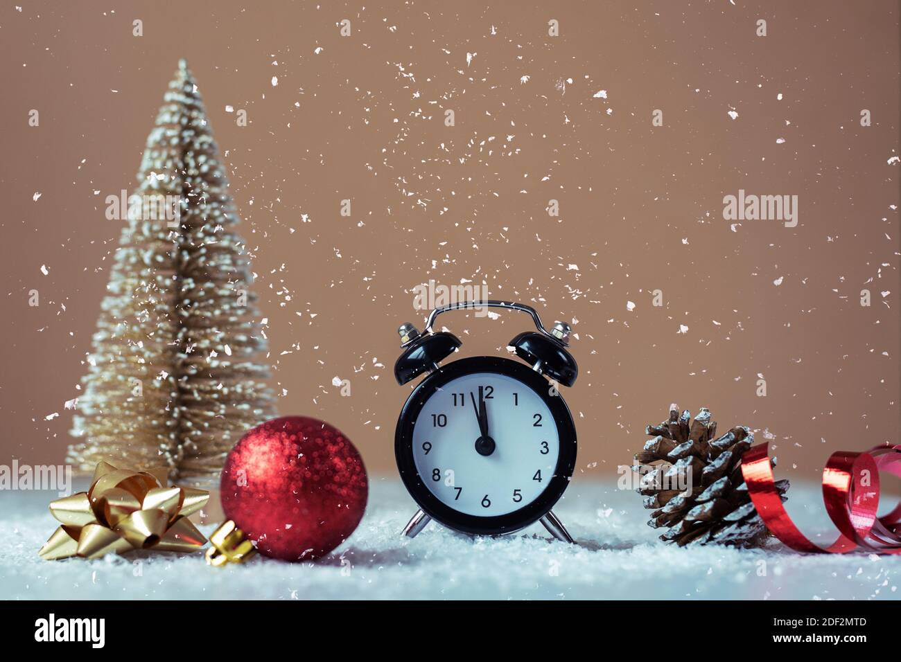 Alarm clock, Christmas tree toy and pine cone on beige background with ...