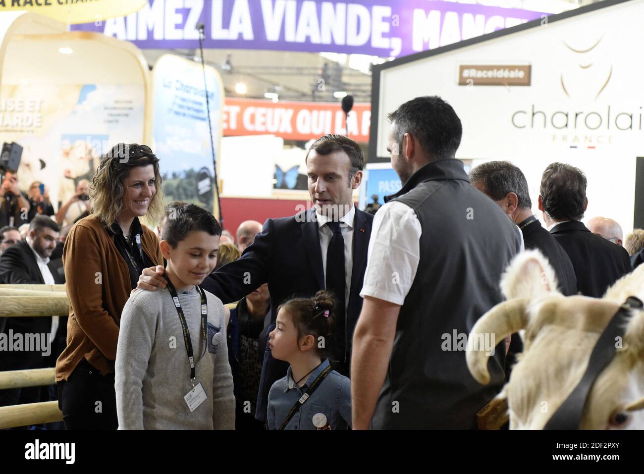 French President Emmanuel Macron talks with a farmer next to a cow ...