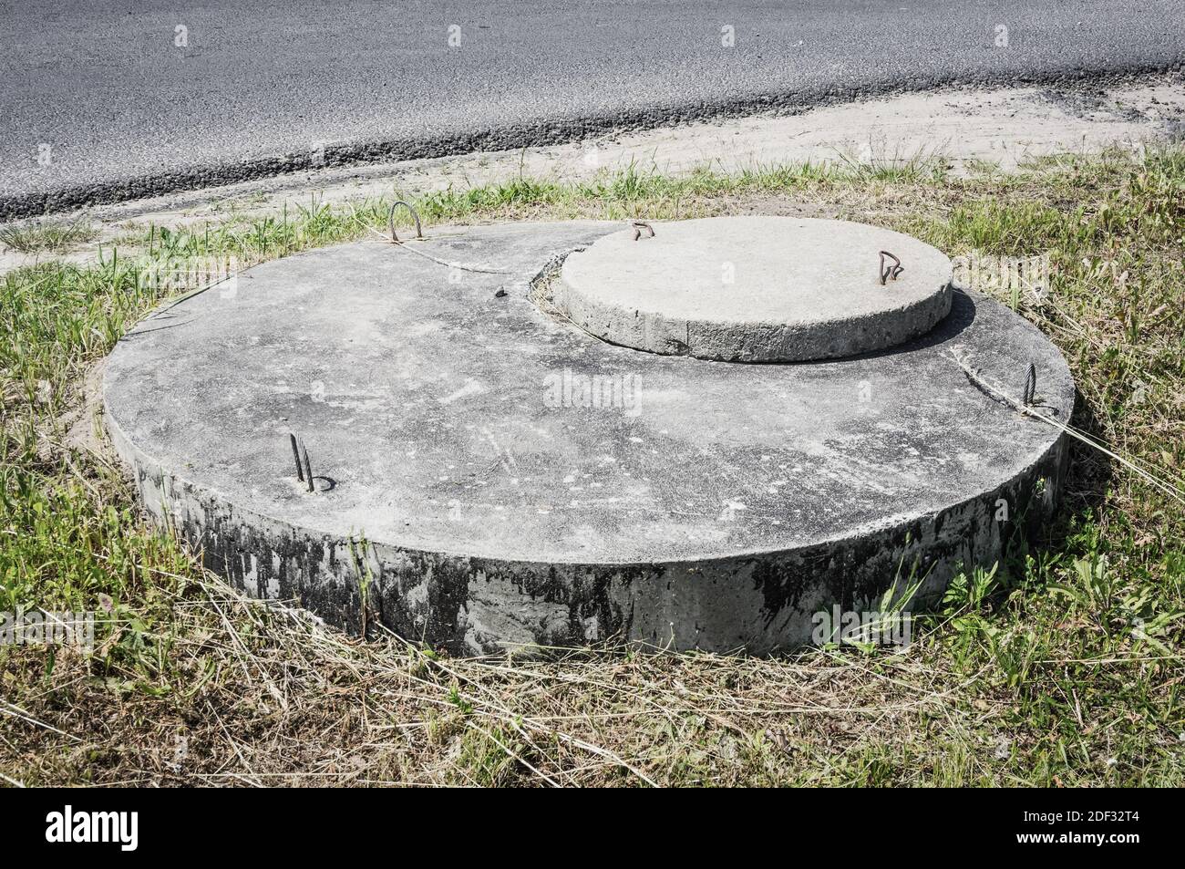 Stone sewer with cover on green grass Stock Photo - Alamy