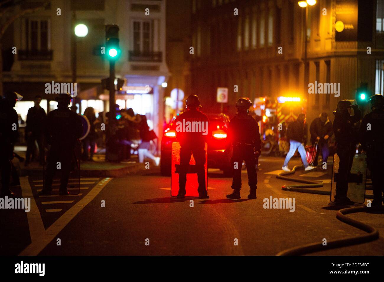 Riot police officers stand near the scene of a fire next to the ...