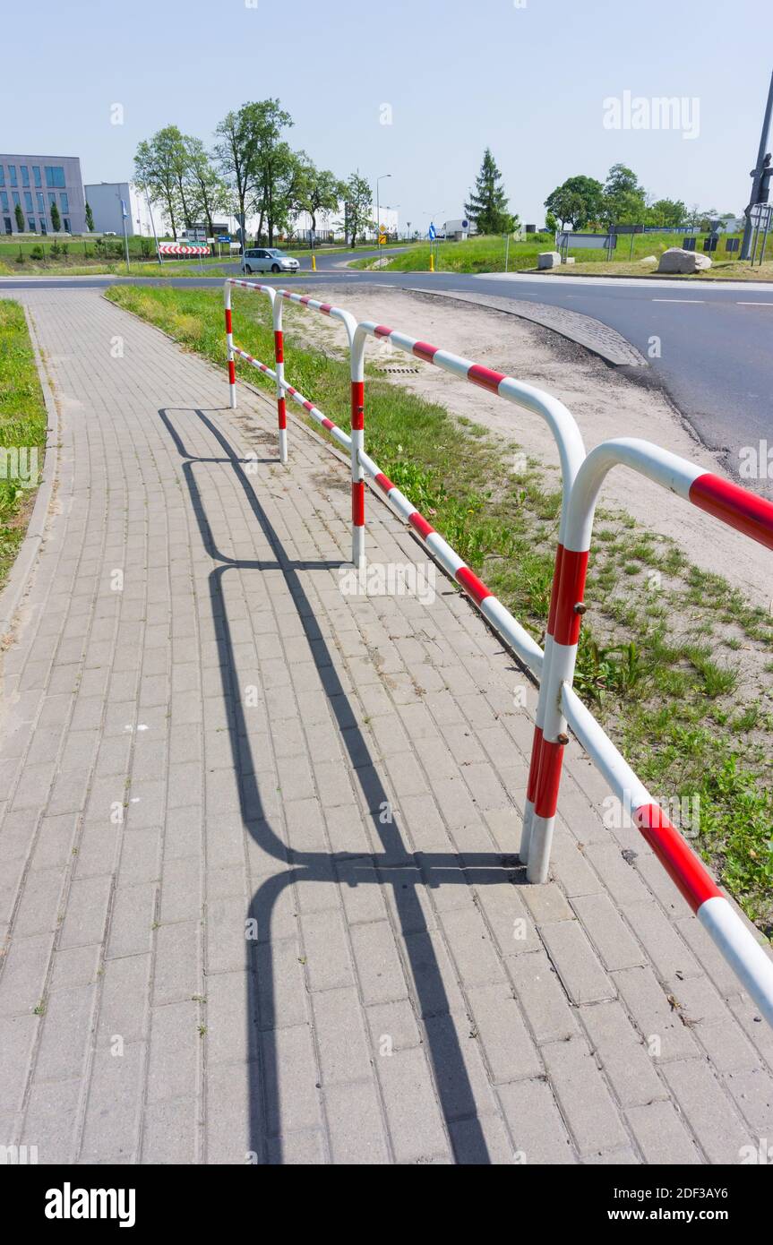 A vertical shot of metal barriers next to a road and its shadow Stock ...