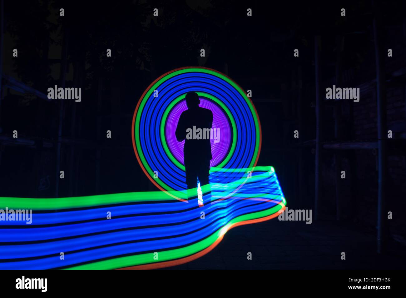 One person standing alone against beautiful color circle LED light ...