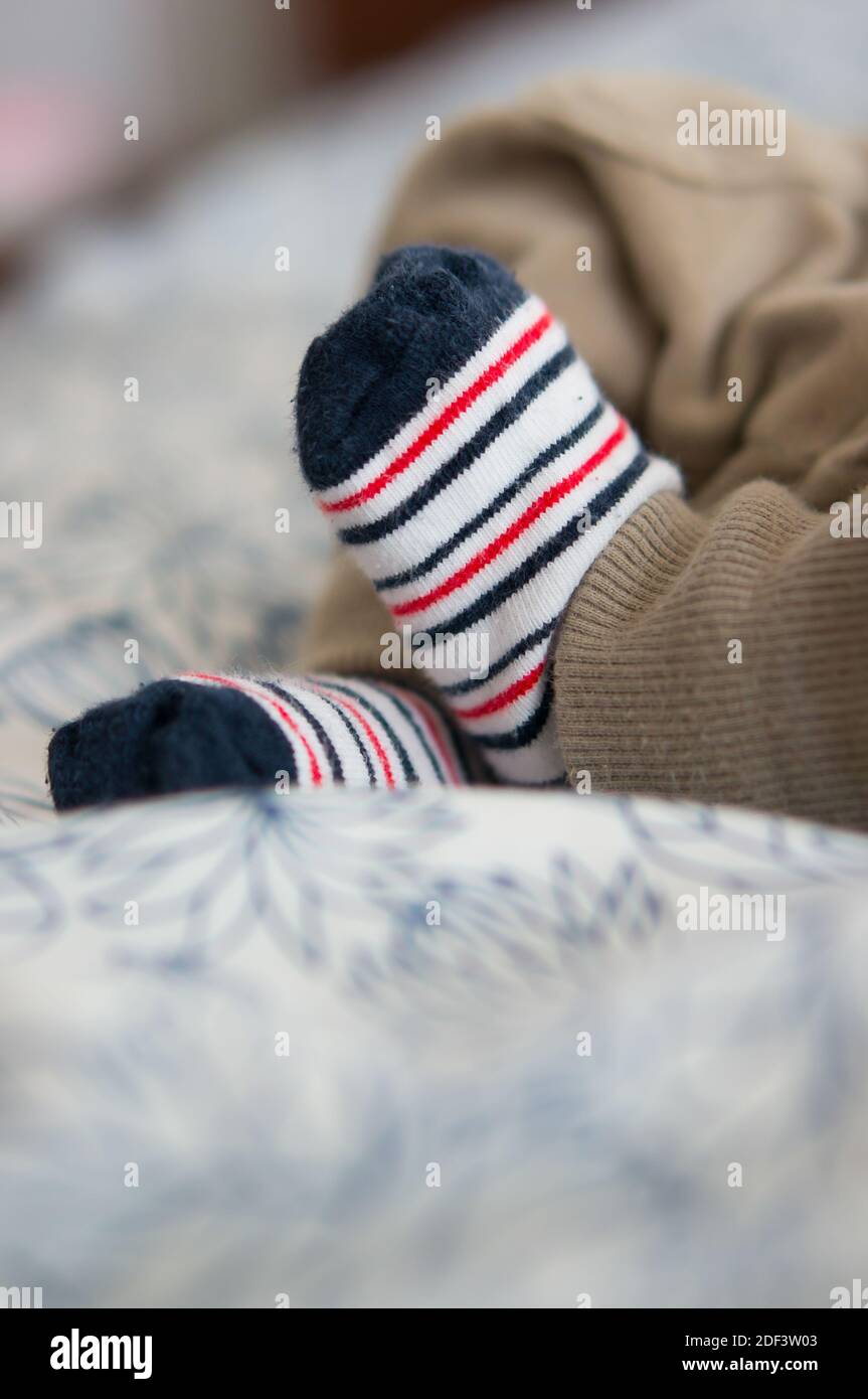 A beautiful shot of the cute baby feet wearing white socks on the bed ...