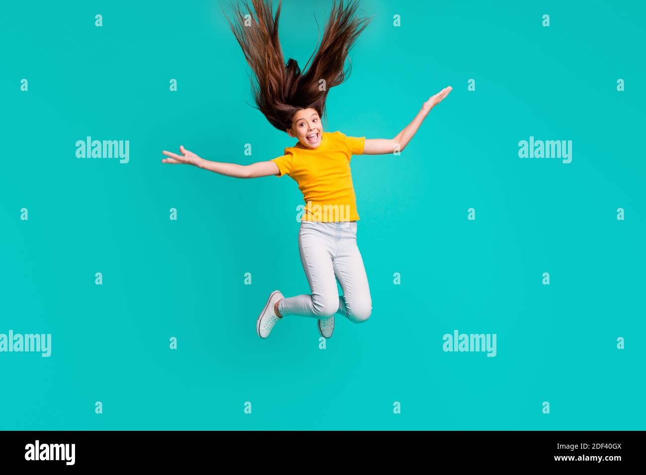 Full size photo of excited kid girl jump high her hair flying wear ...