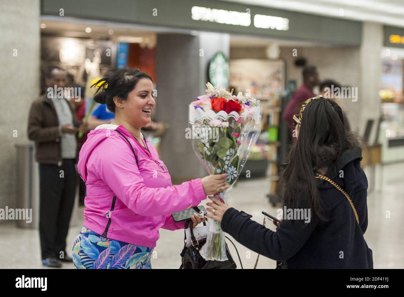 A woman is given a bouquet of flowers as she arrives from Dubai after a ...