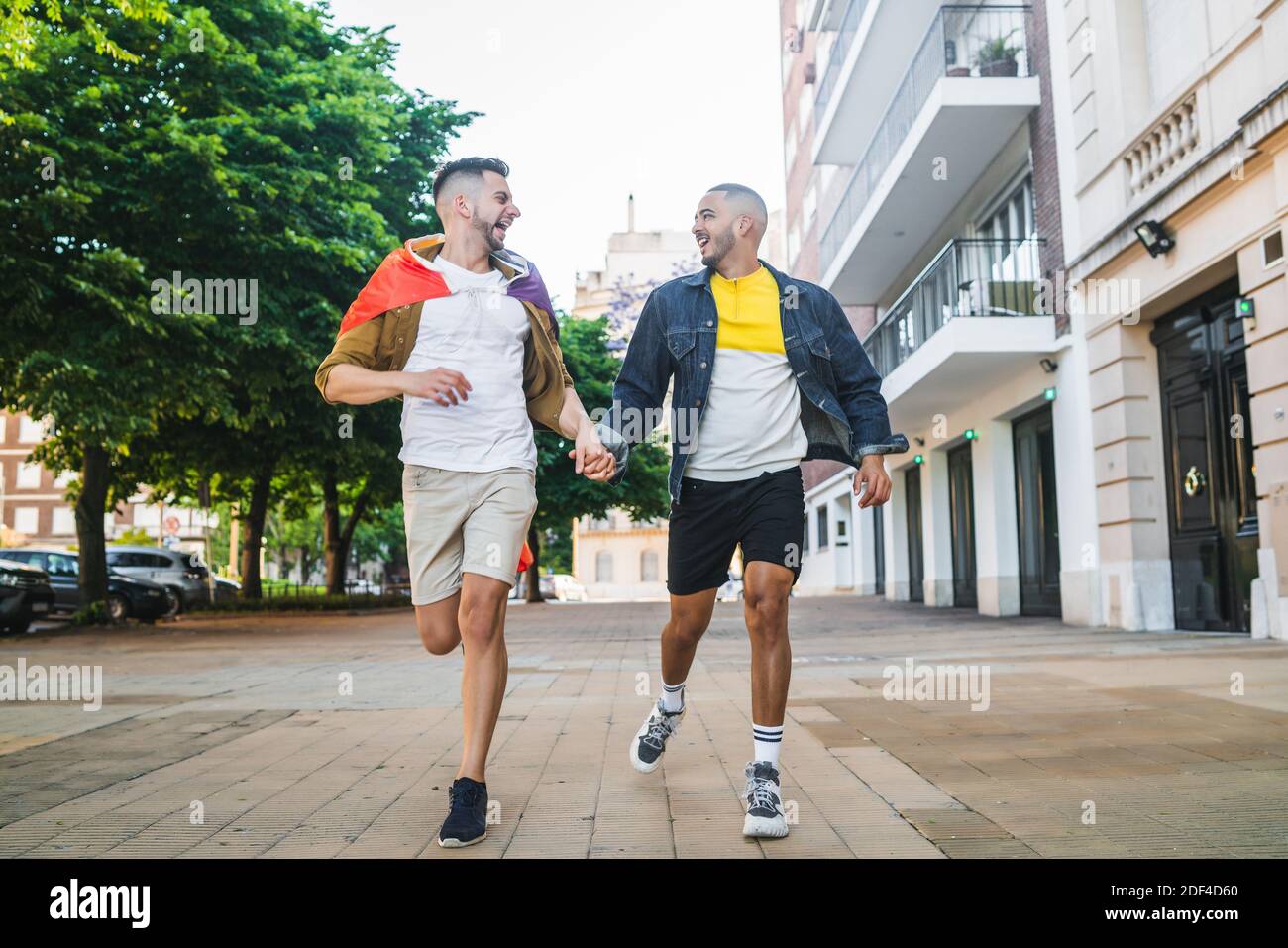 Gay couple holding their hands and running together Stock Photo - Alamy