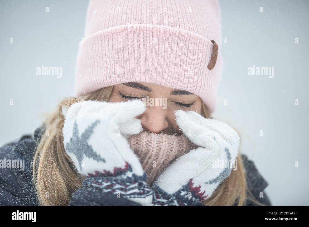 Female closing here eyes and warming up her hands on a very cold day ...