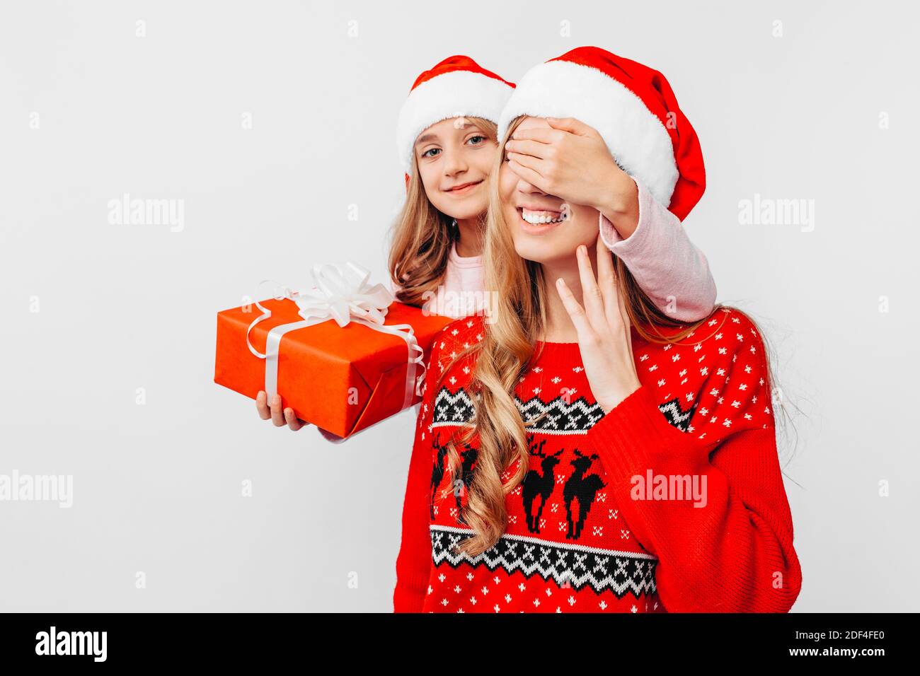 Daughter with mom in Santa hats and Christmas sweaters, daughter gives ...