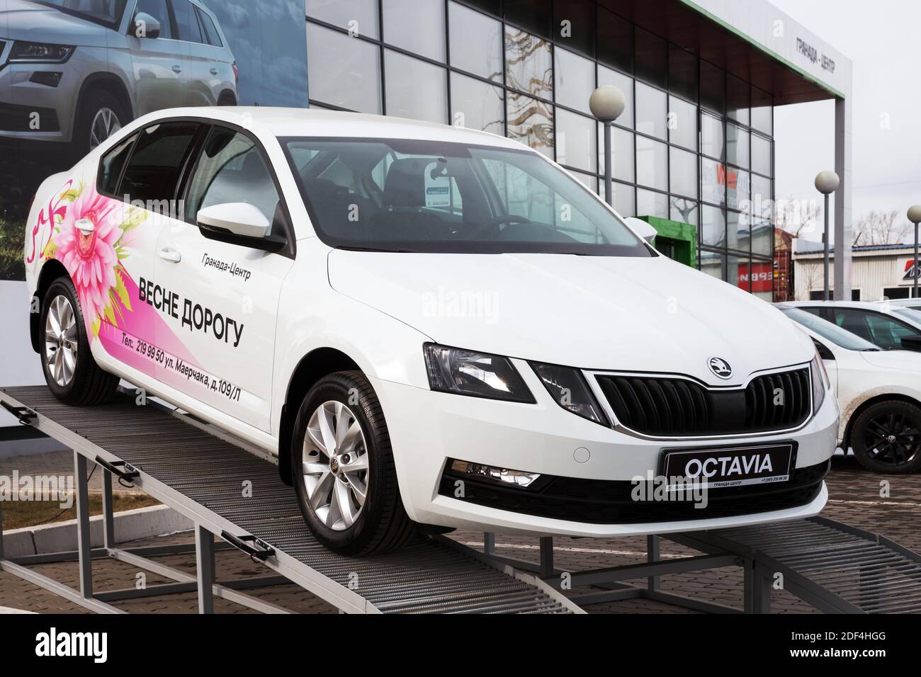 A car with an advertisement on its body stands on a podium near the ...