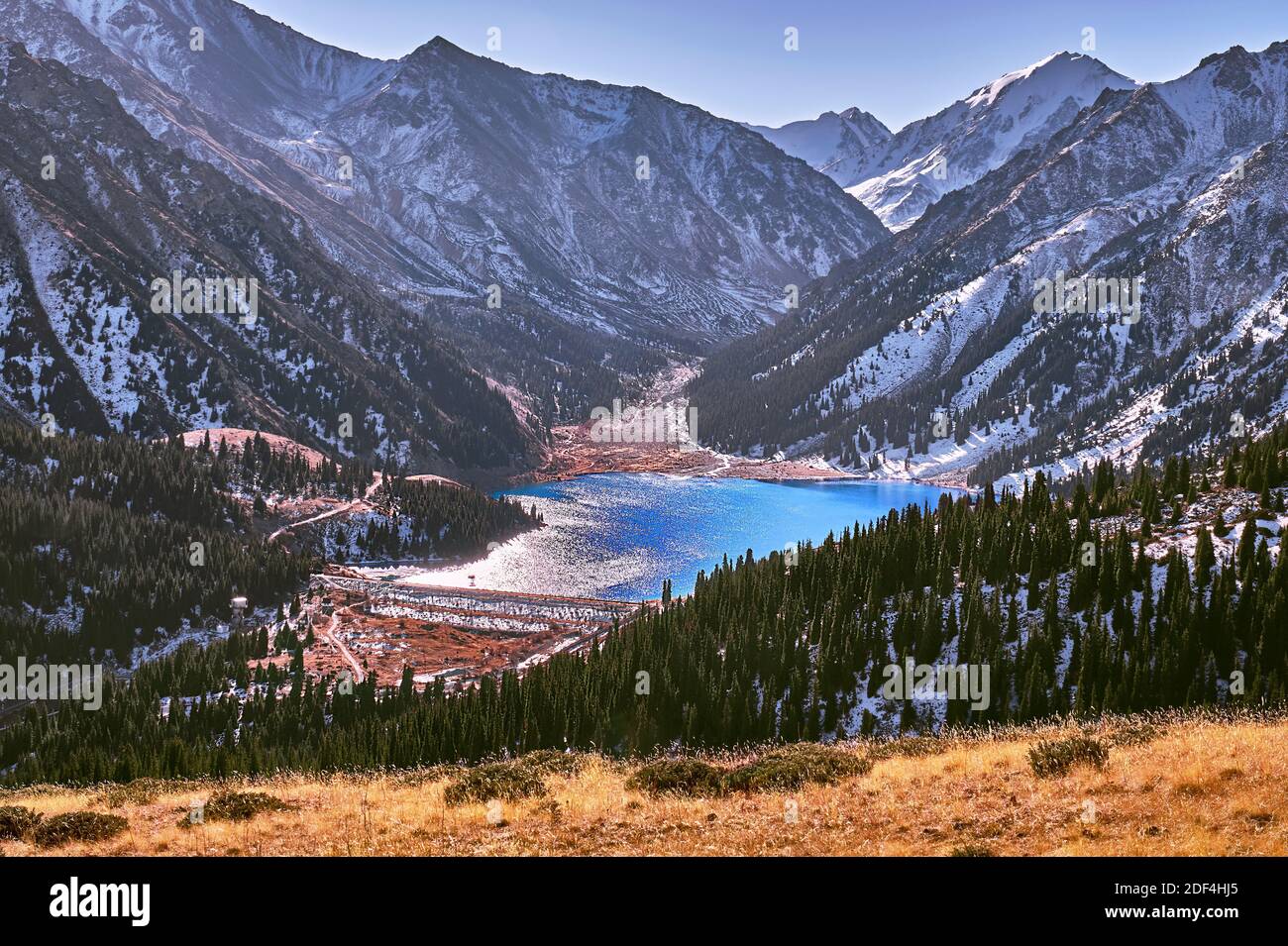Turquoise lake among snow-capped mountains on a sunny days in winter ...