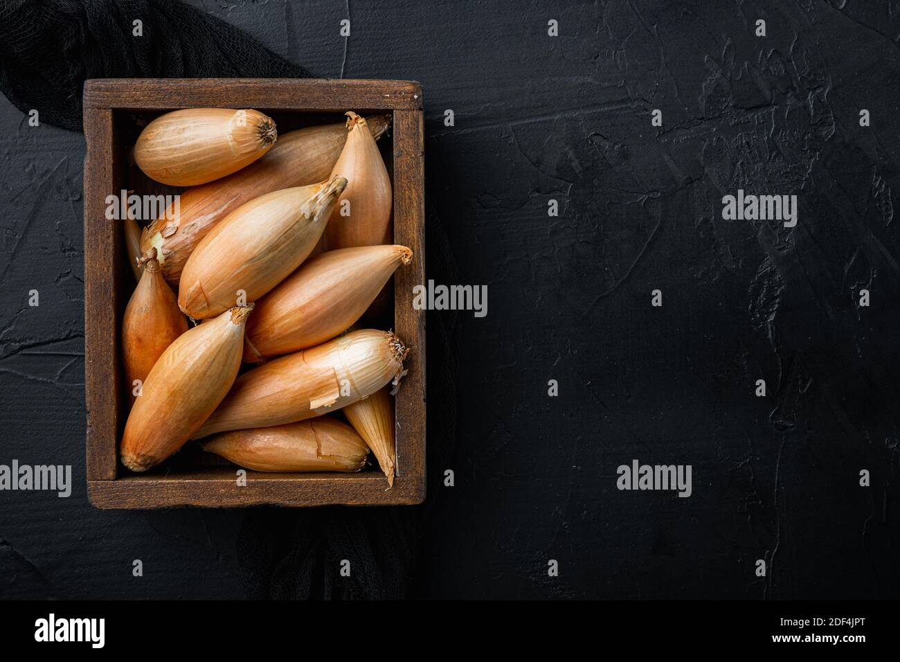 Raw whole baby shallot onion, on black textured background, flat lay ...