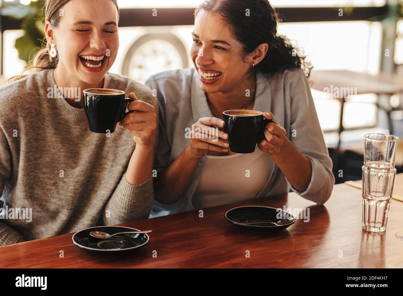 Happy woman friends in a cafe having coffee. Two females sitting at a ...