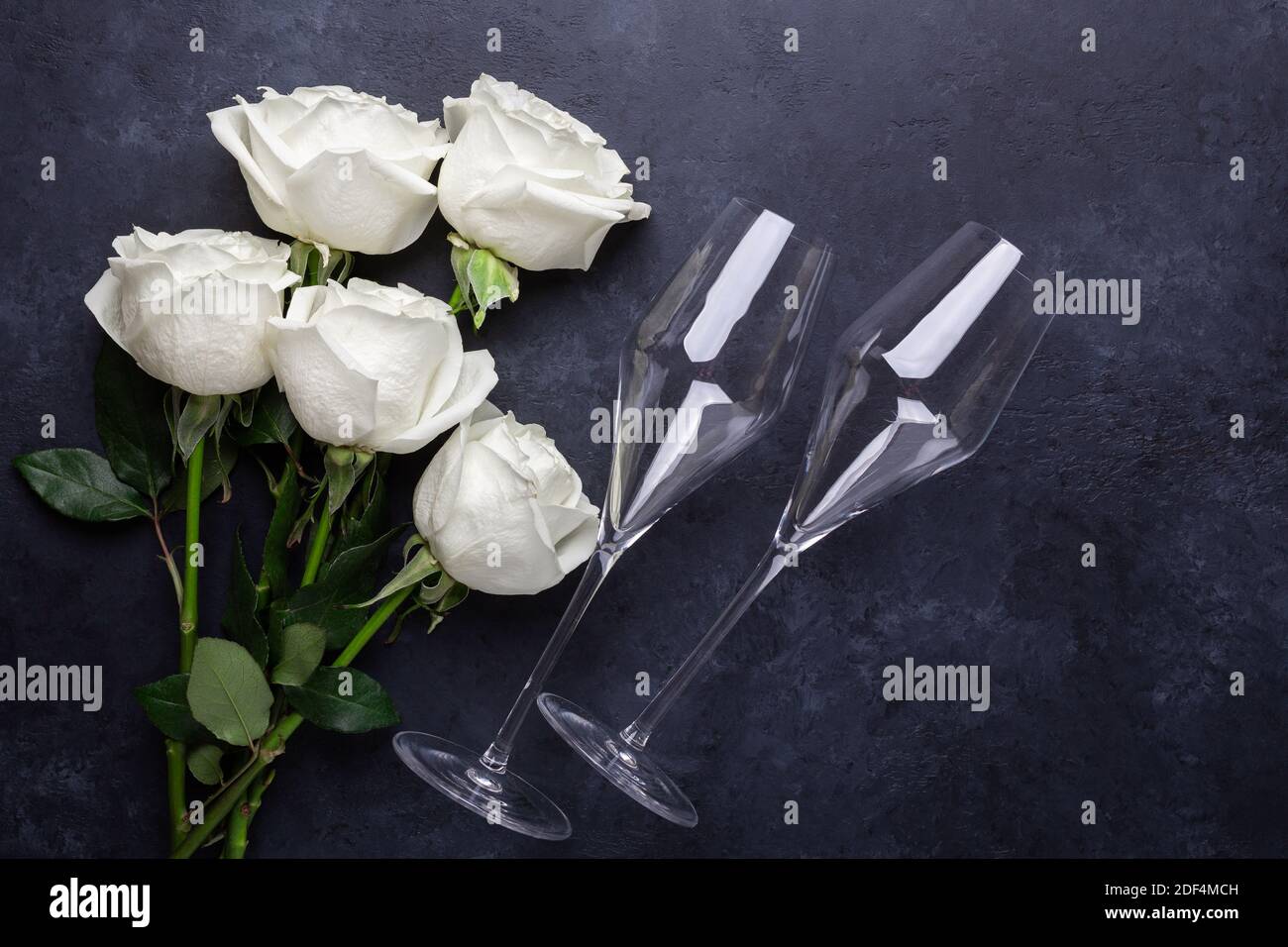 Romantic still life. White rose flowers and champagne glasses on black ...