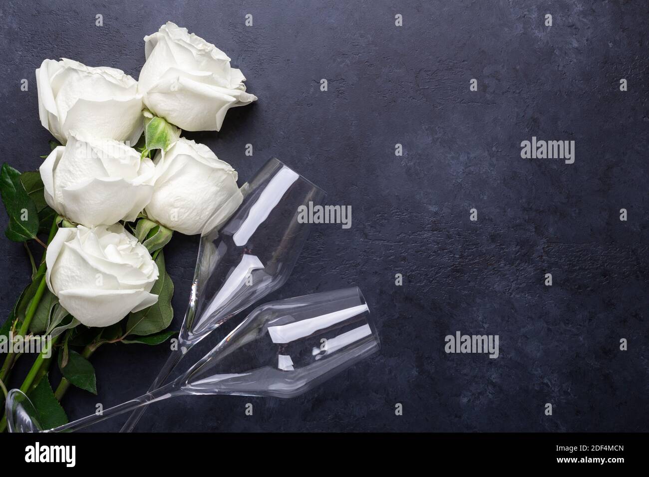 Romantic still life. White rose flowers and champagne glasses on black ...