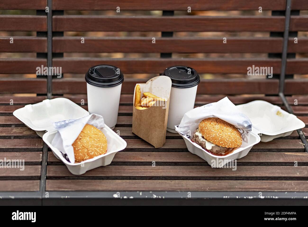 Fast food. Paper cups with coffee, hamburger boxes and fries on a park ...