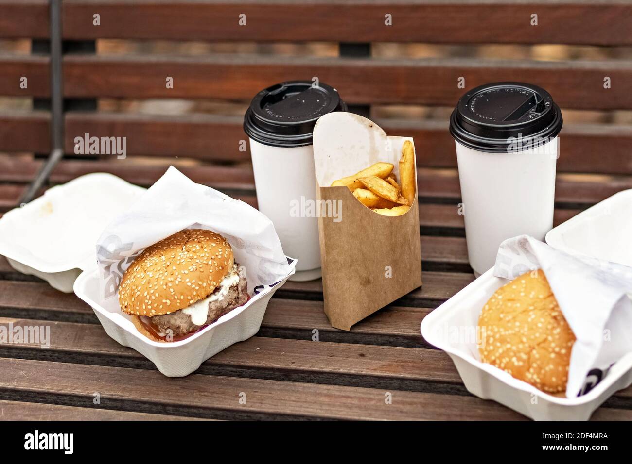 Fast food. Paper cups with coffee, hamburger boxes and fries on a park ...