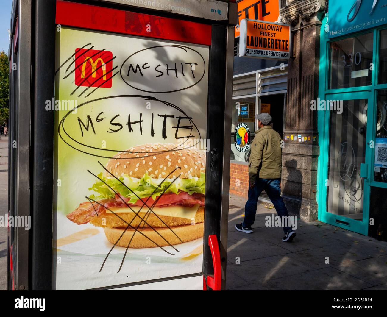 Anti MacDonalds graffitti on a phone box advert Stock Photo - Alamy