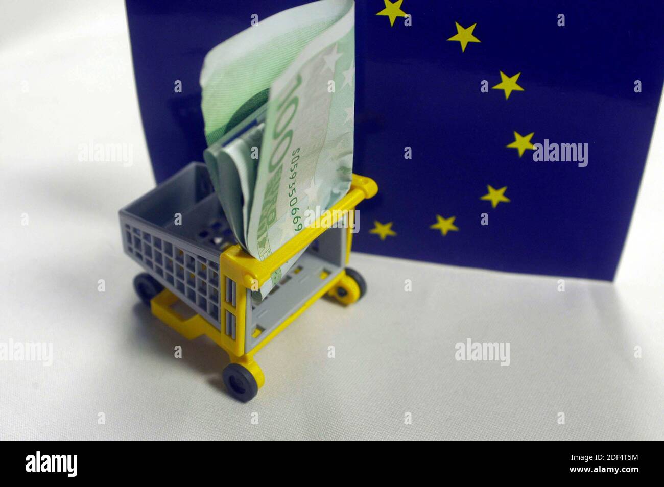 euro banknotes and small toy shopping cart, cash money as means of ...