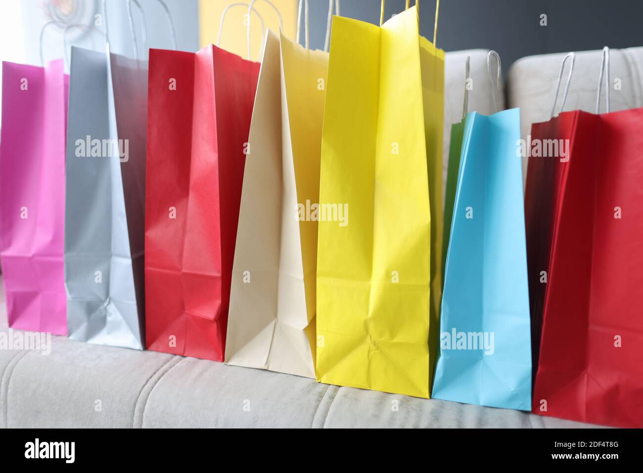Many multi-colored paper bags with purchases standing on the sofa at ...