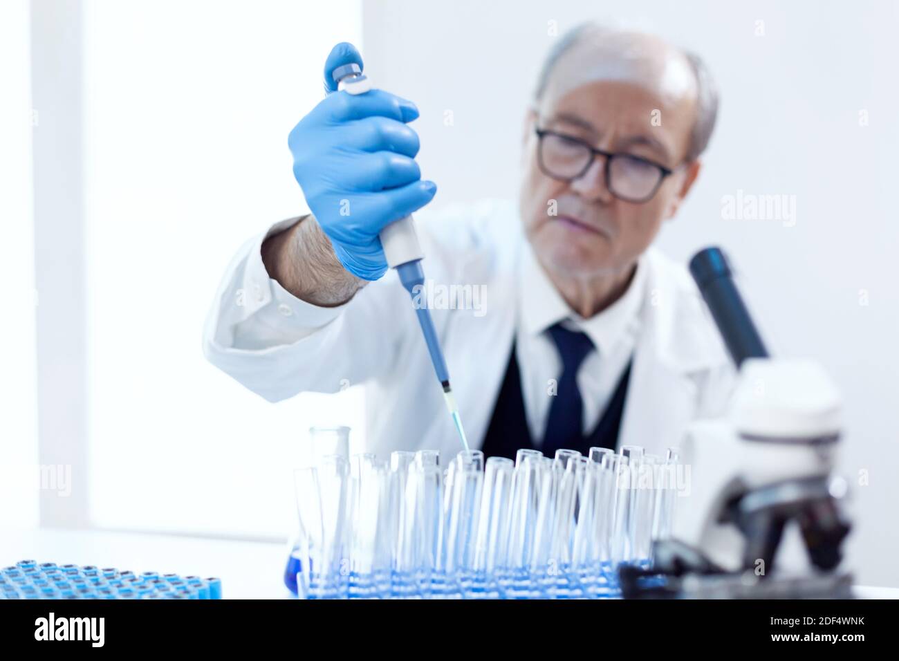 Pharmaceutical scientist pouring blue substange in test tubes sitting ...