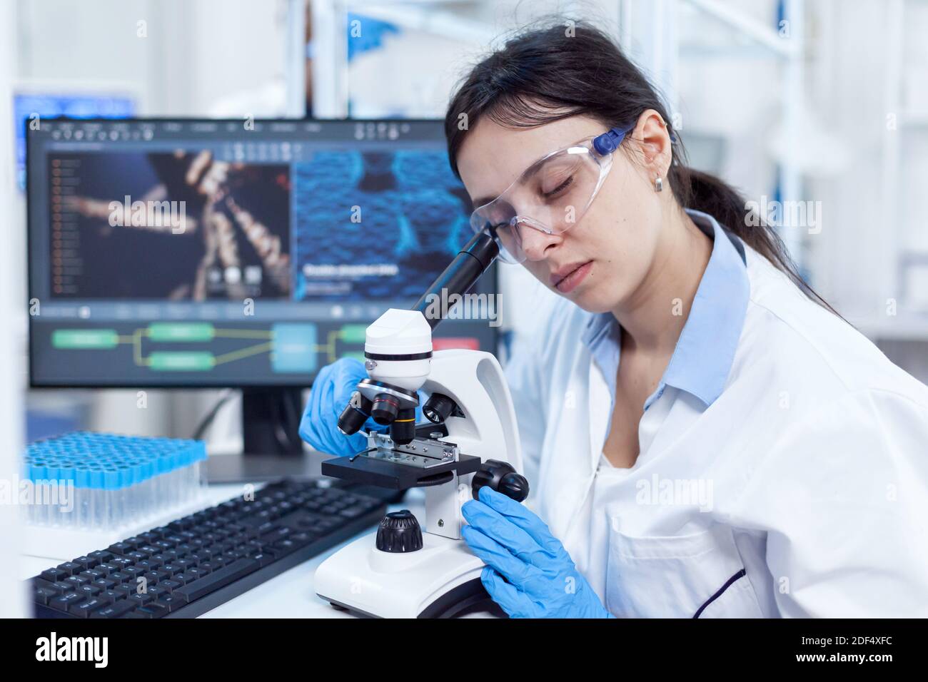 Female scientist in modern lab uses microscope for medicine vacine ...