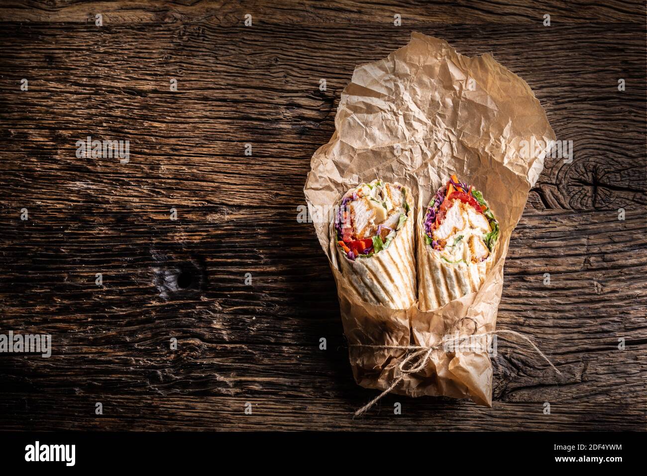 Grilled tortilla wraps with chicken and veggies wrapped in a paper ...