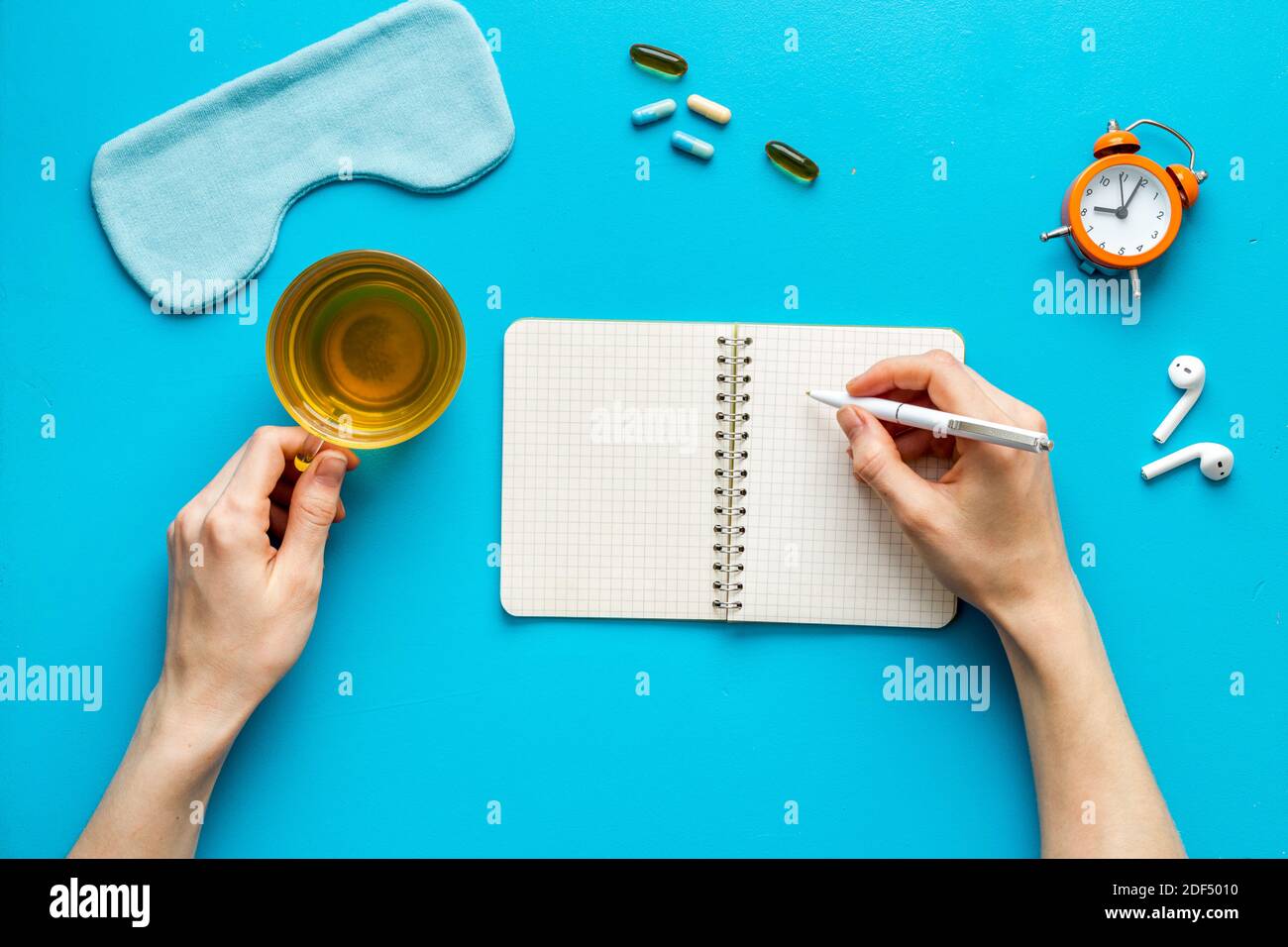 Female hand write in notebook - day plan before sleeping. Top view ...