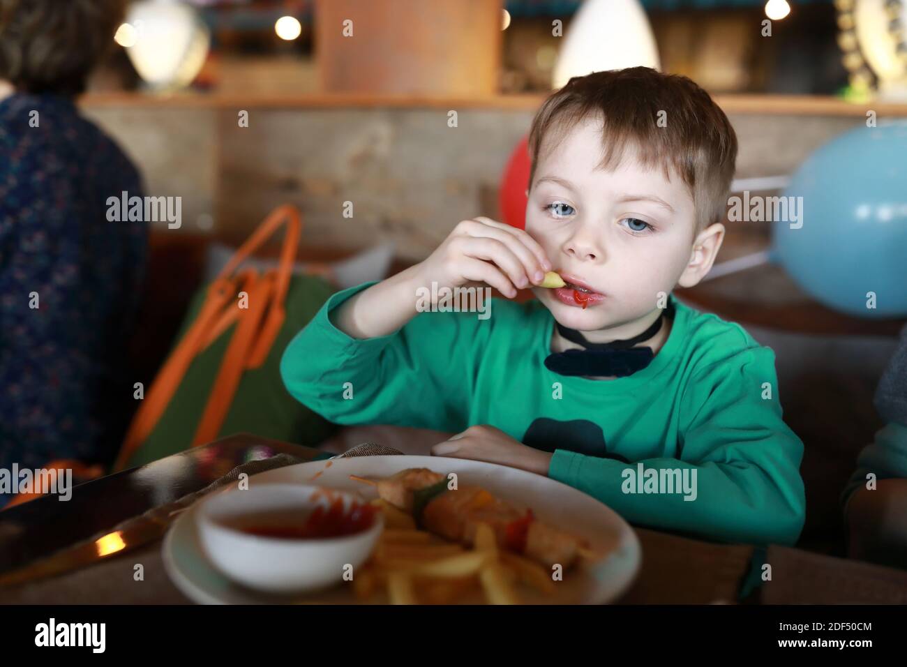Child eating french fries in a restaurant Stock Photo - Alamy
