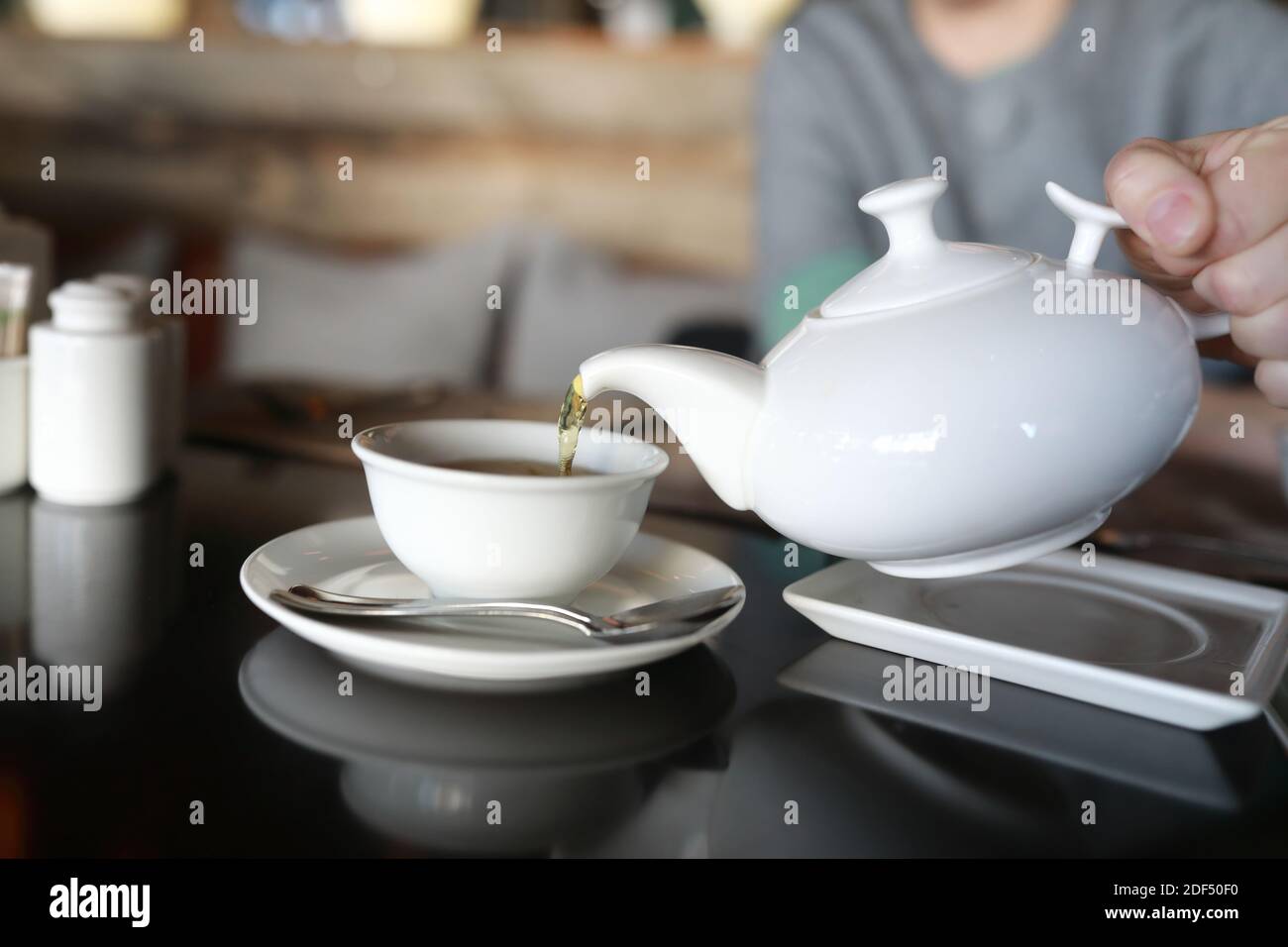 Woman pours tea from white teapot in restaurant Stock Photo - Alamy