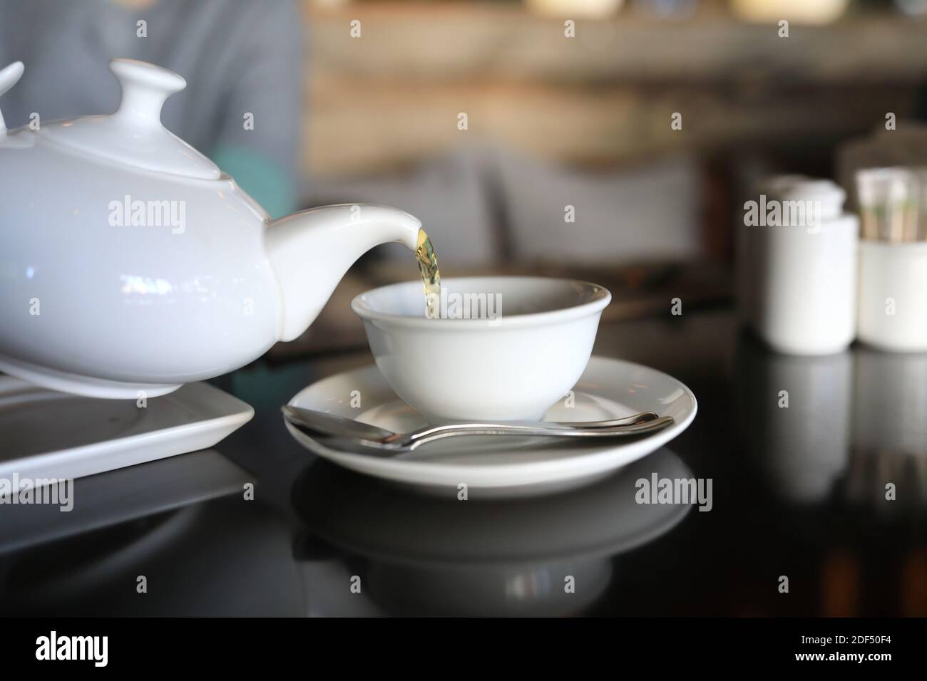 Person pours tea from white teapot in restaurant Stock Photo - Alamy