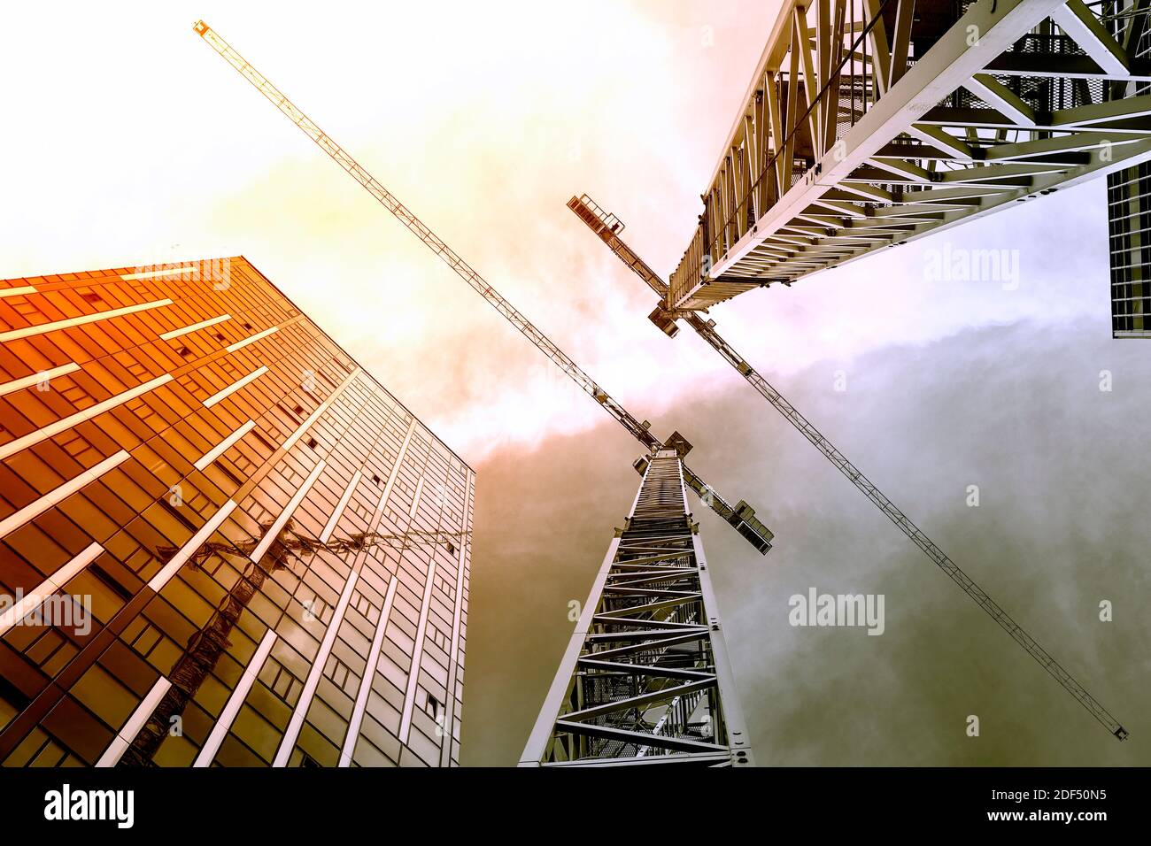 Tower crane. Bottom view of a tall construction cranes next to a modern ...