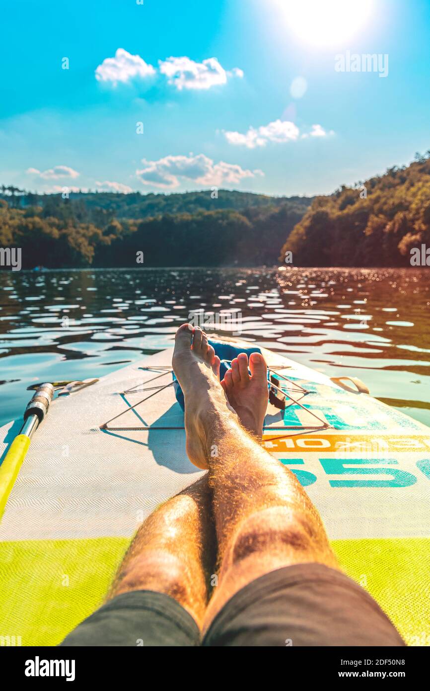 View on men's feet on a paddleboard. Close-up of legs on surf. Relax ...