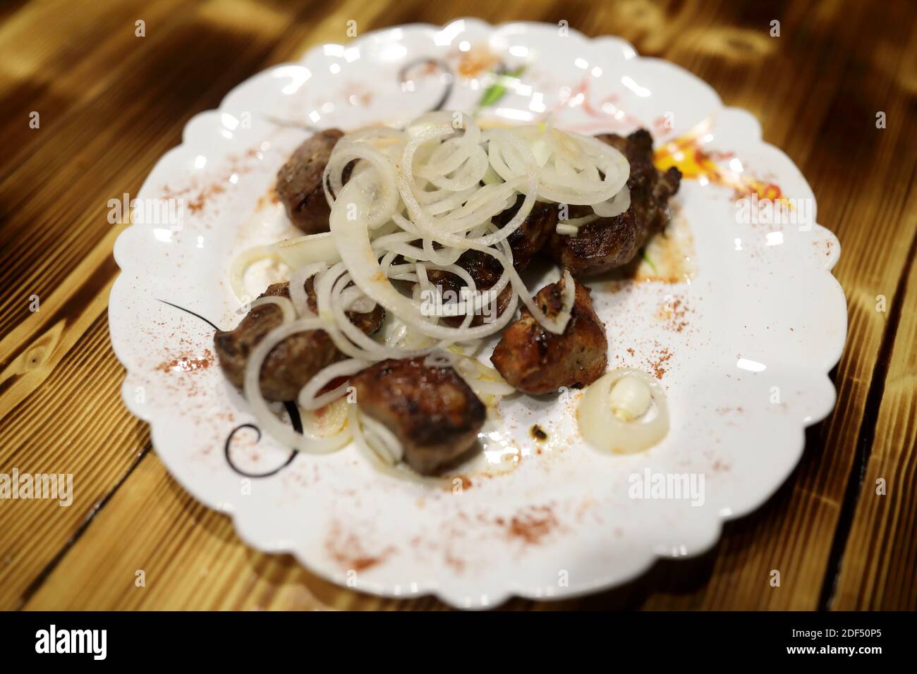 Slices of kebab with onion rings on plate in restaurant Stock Photo - Alamy