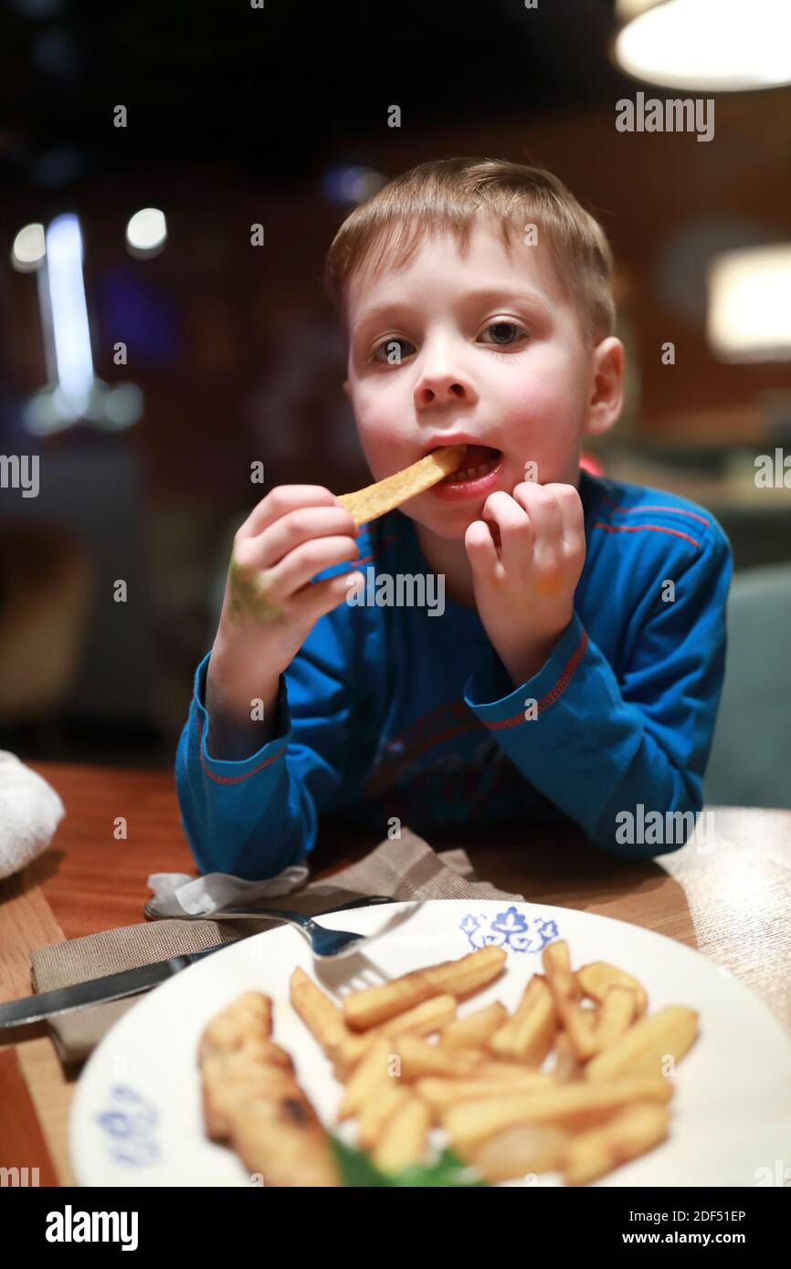 Child eating fried potatoes in the restaurant Stock Photo - Alamy