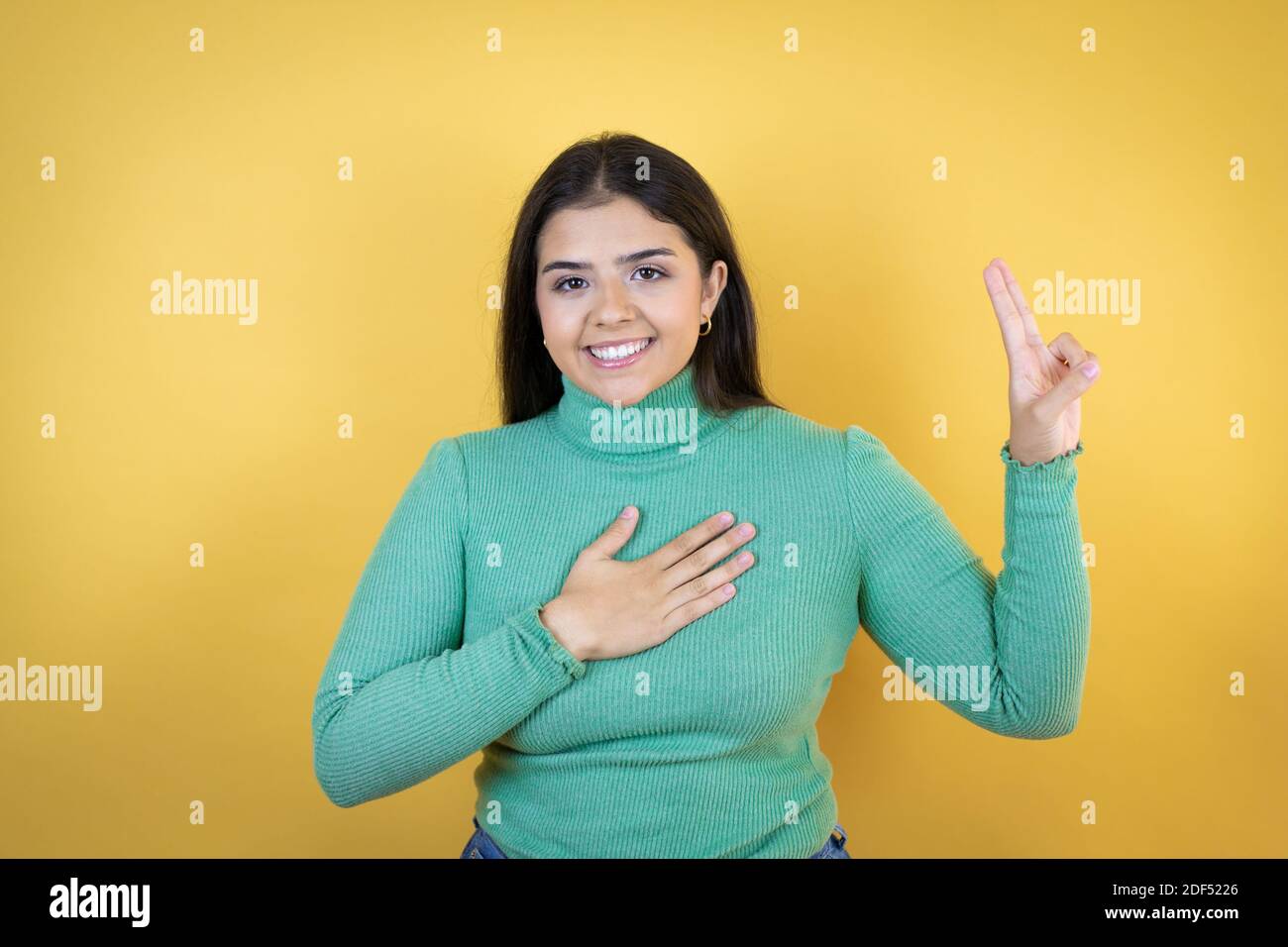 Young caucasian woman over isolated yellow background smiling swearing ...