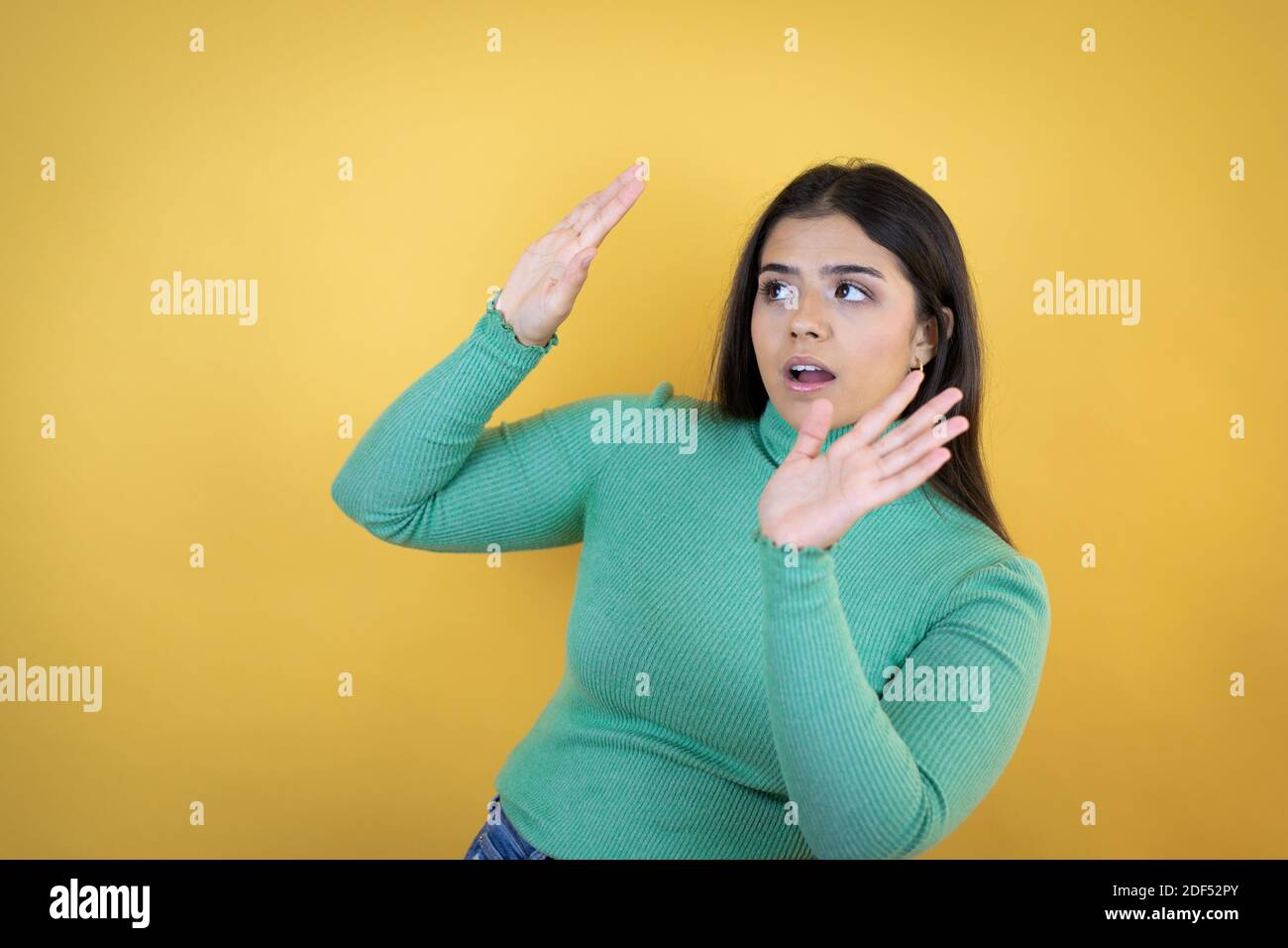 Young caucasian woman over isolated yellow background scared with her ...