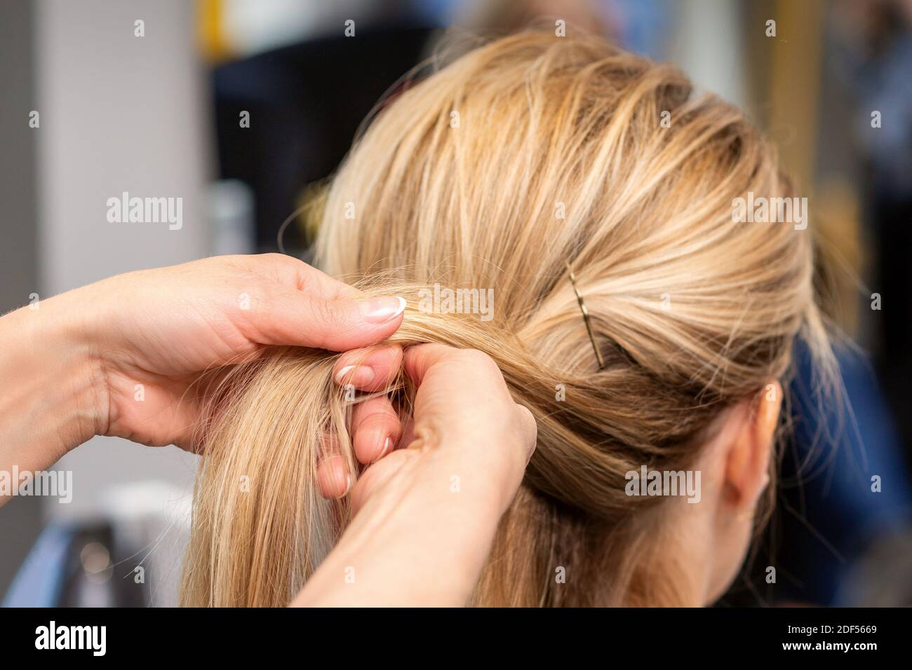 Close up of the hairdresser's hands braiding the client's hair in ...