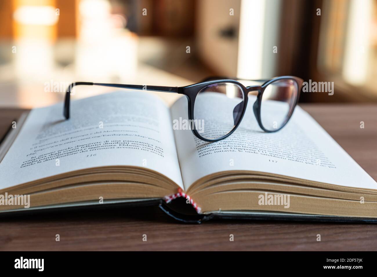 Books open, one on top, with eyeglasses on top Stock Photo - Alamy