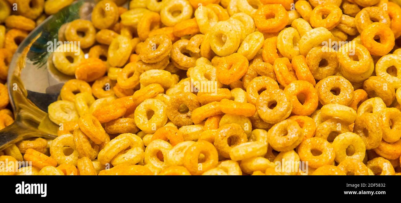A closeup shot of golden round-shaped cereals and a metal spoon in it ...
