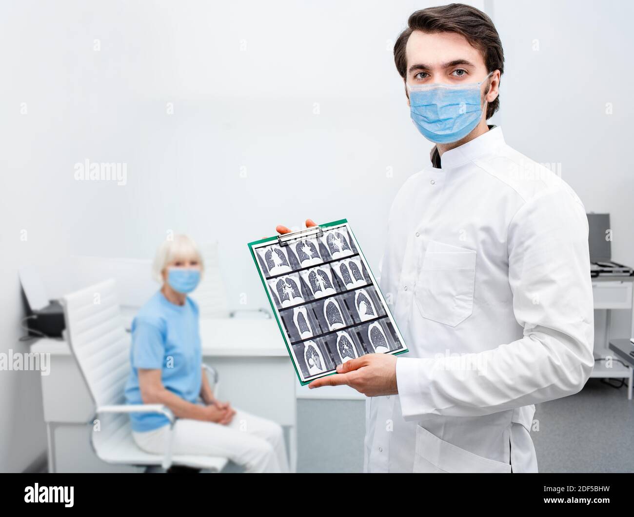 Pulmonologist wearing protective mask showing CT scan of lungs elderly ...