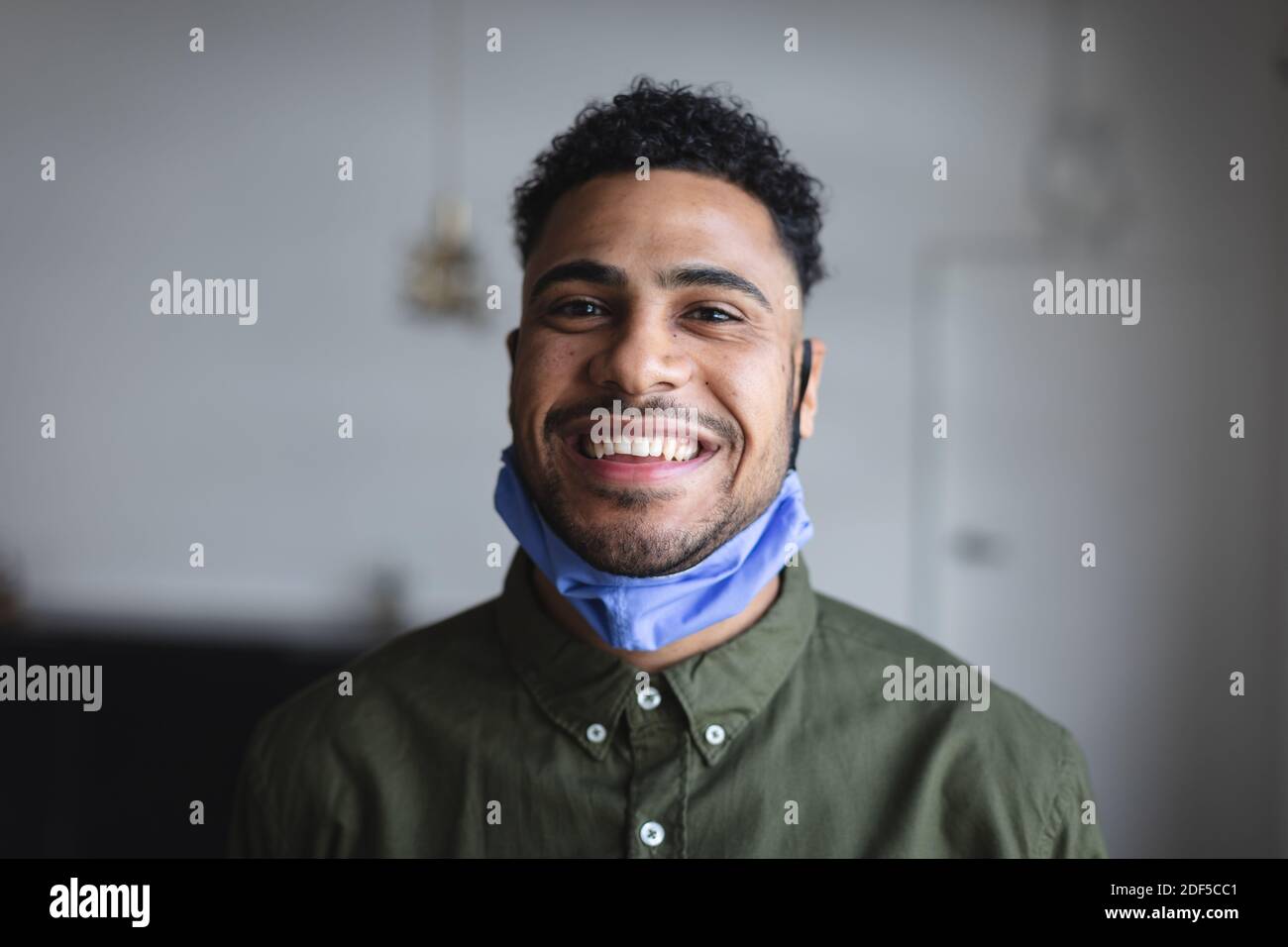 Portrait of middle eastern man with lowered face mask against grey ...