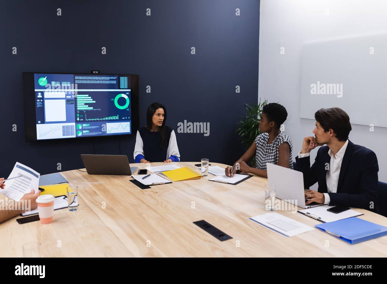 Diverse business people in conference room discussing using laptop ...