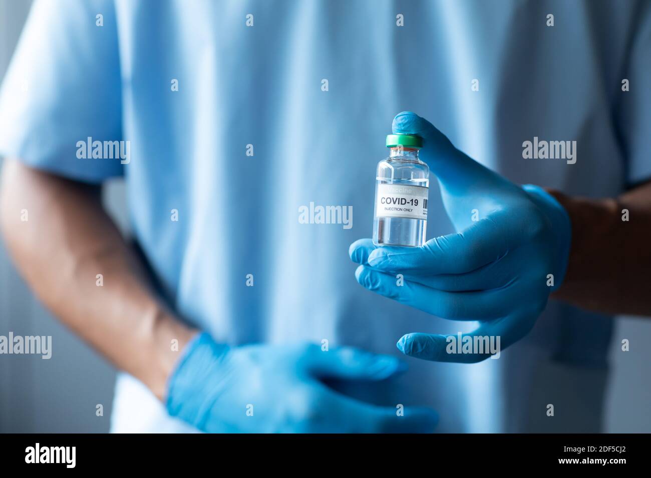 Midsection of male doctor holding covid-19 vaccination wearing face ...