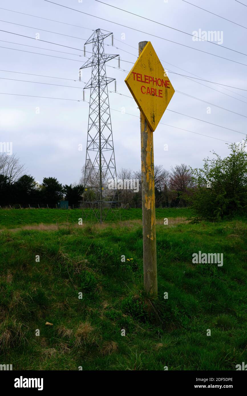 A yellow warning marker sign for an underground telephone cable ...