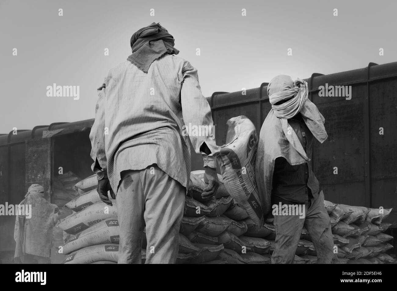 Man wearing only head scarf as protection employed to move bags of ...